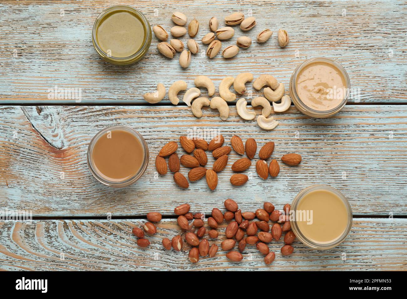 Different types of delicious nut butters and ingredients on light blue ...