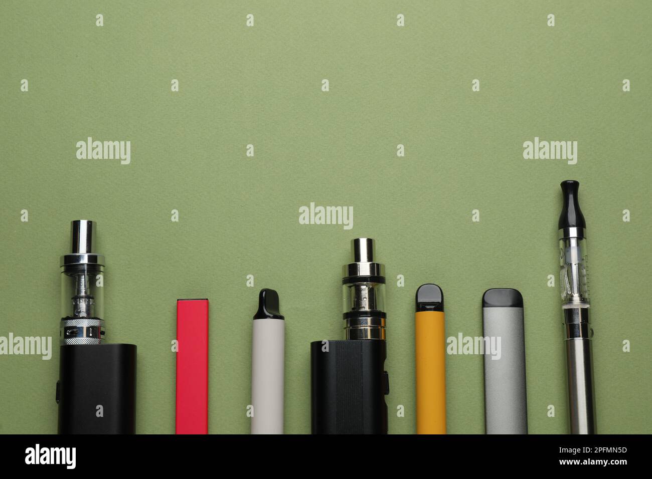 Many electronic smoking devices on olive background, flat lay. Space ...