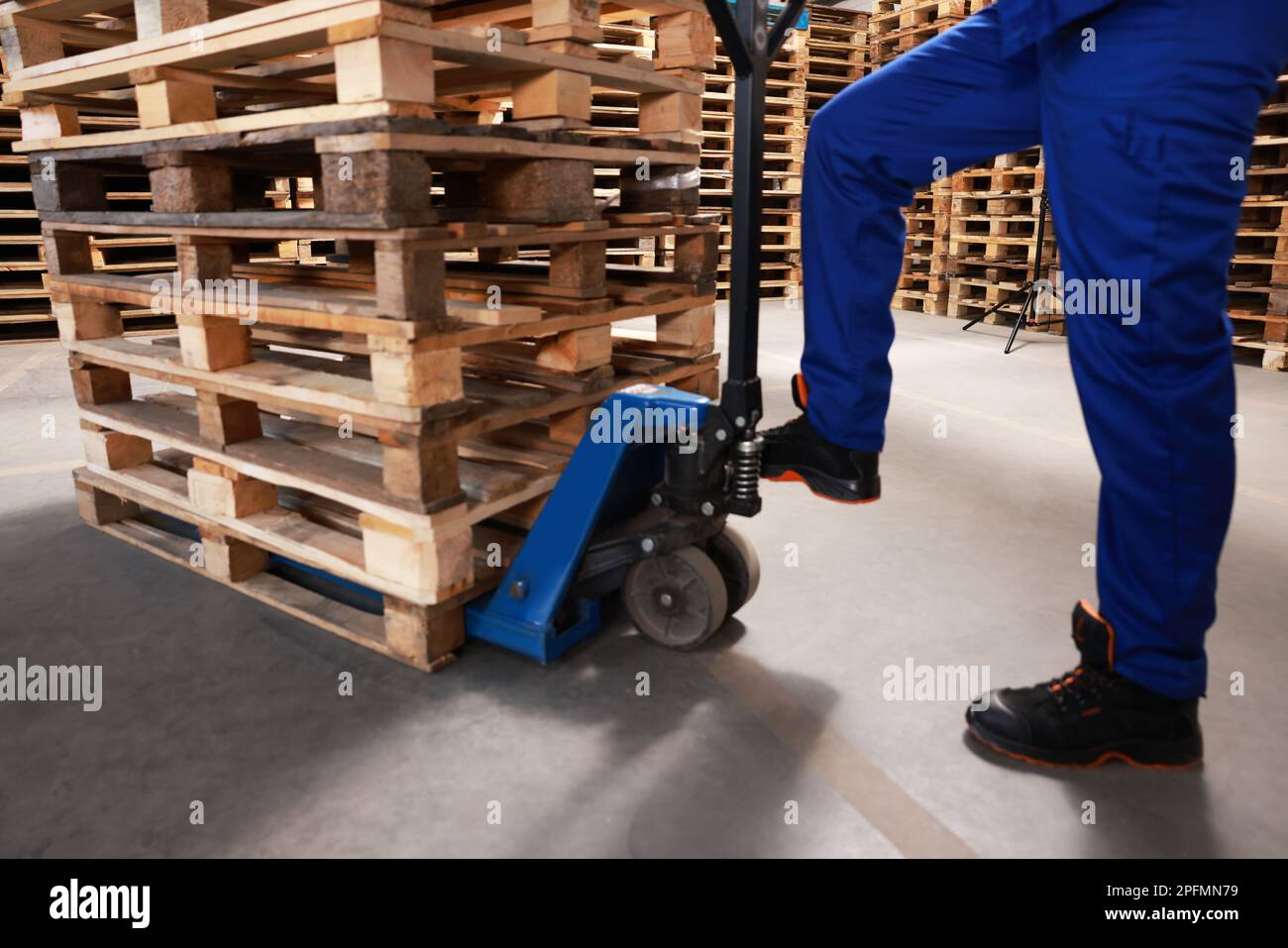 Worker moving wooden pallets with manual forklift in warehouse, closeup ...