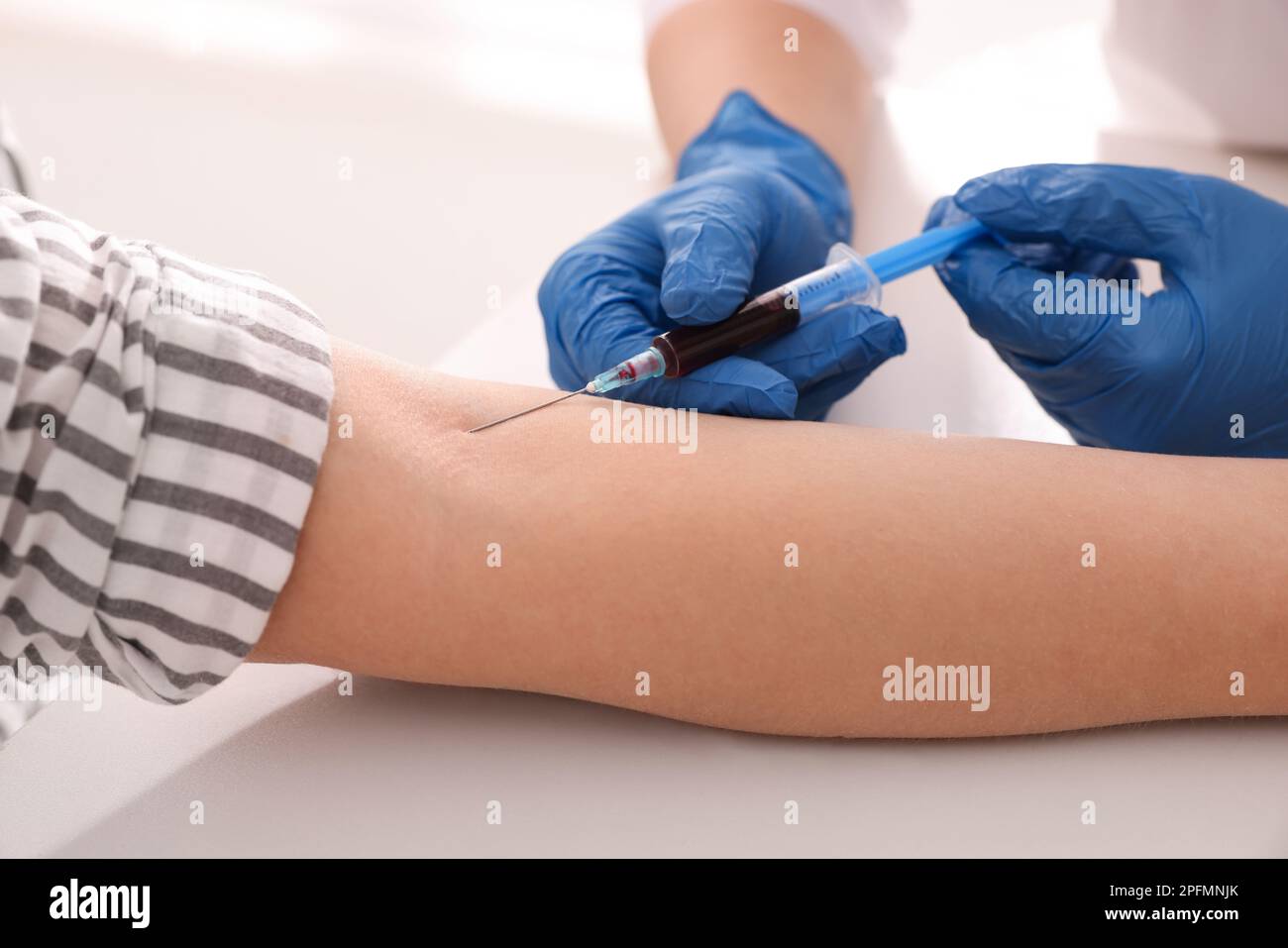 Doctor drawing blood sample of patient with syringe in hospital ...