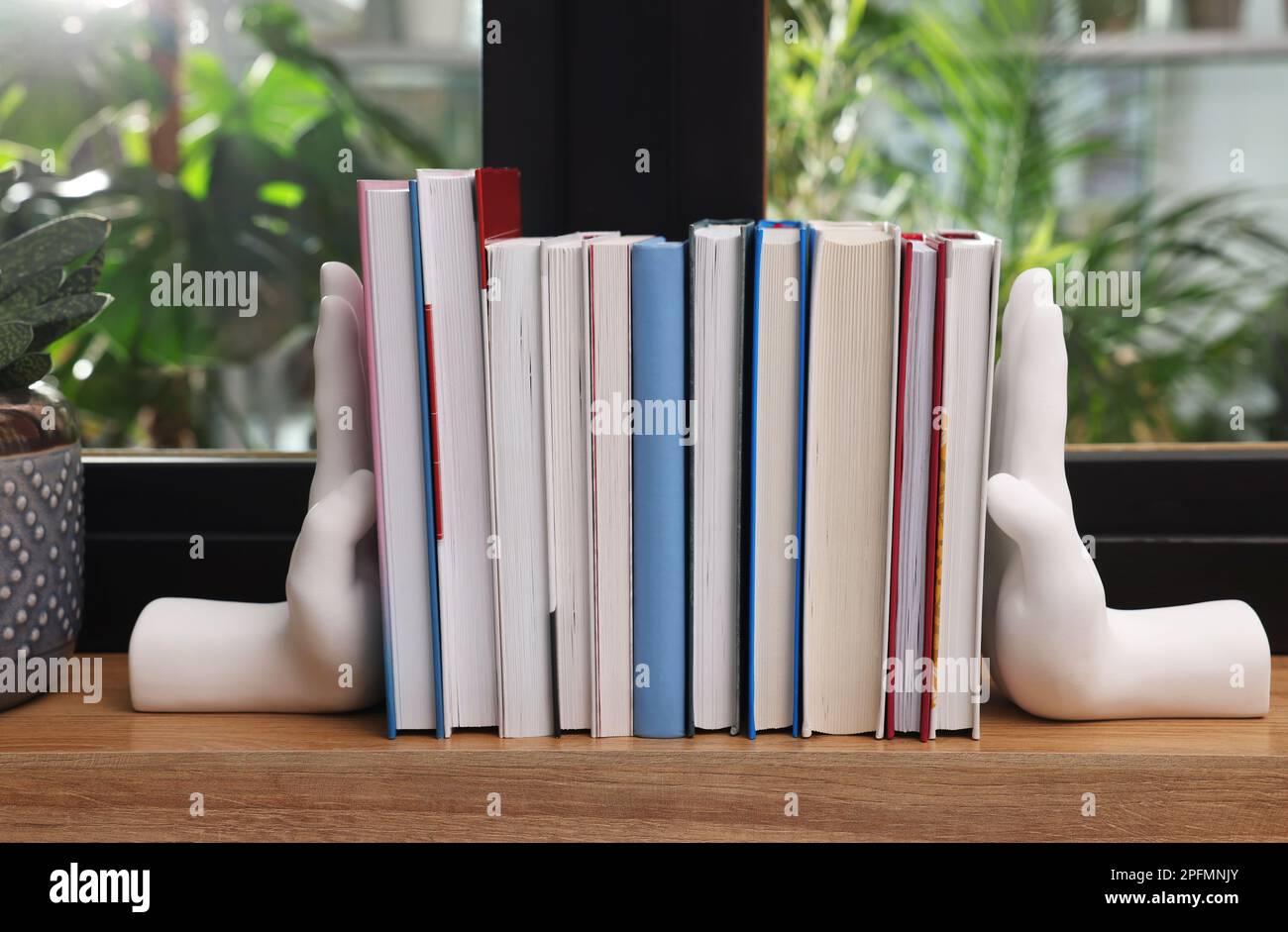 Beautiful hand shaped bookends with books on window sill indoors Stock ...