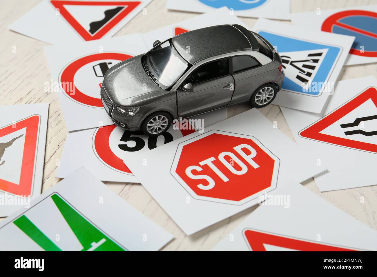 Cards with different road signs and toy car on white wooden table ...