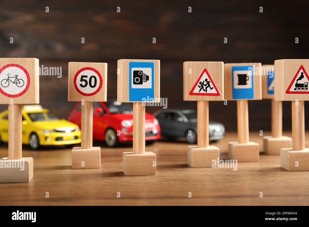 Many different miniature road signs and cars on wooden table. Driving ...