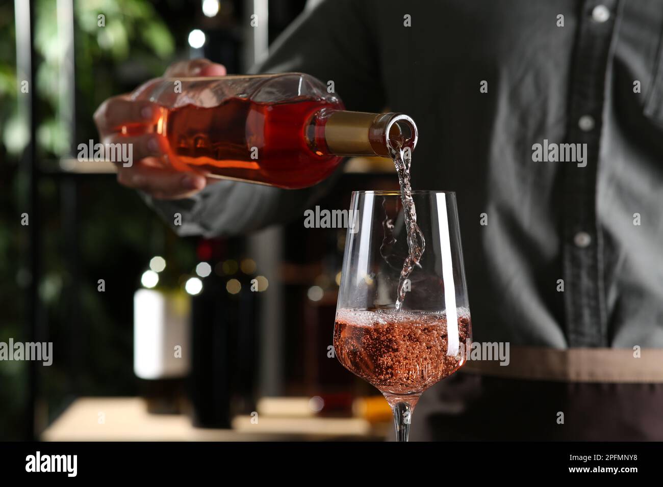Man pouring rose wine from bottle into glass indoors, closeup Stock ...