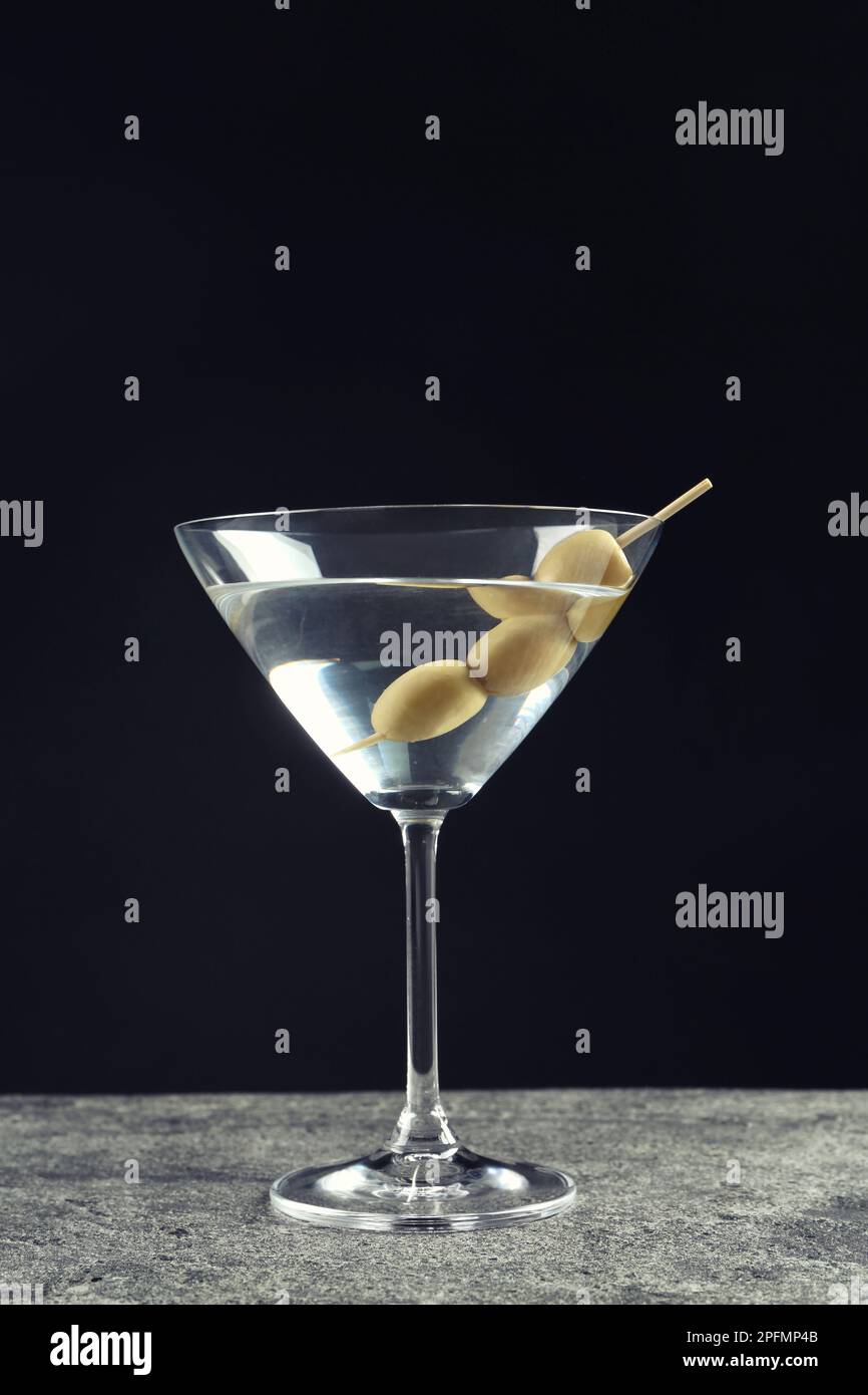 Martini cocktail with olives on grey table against dark background ...
