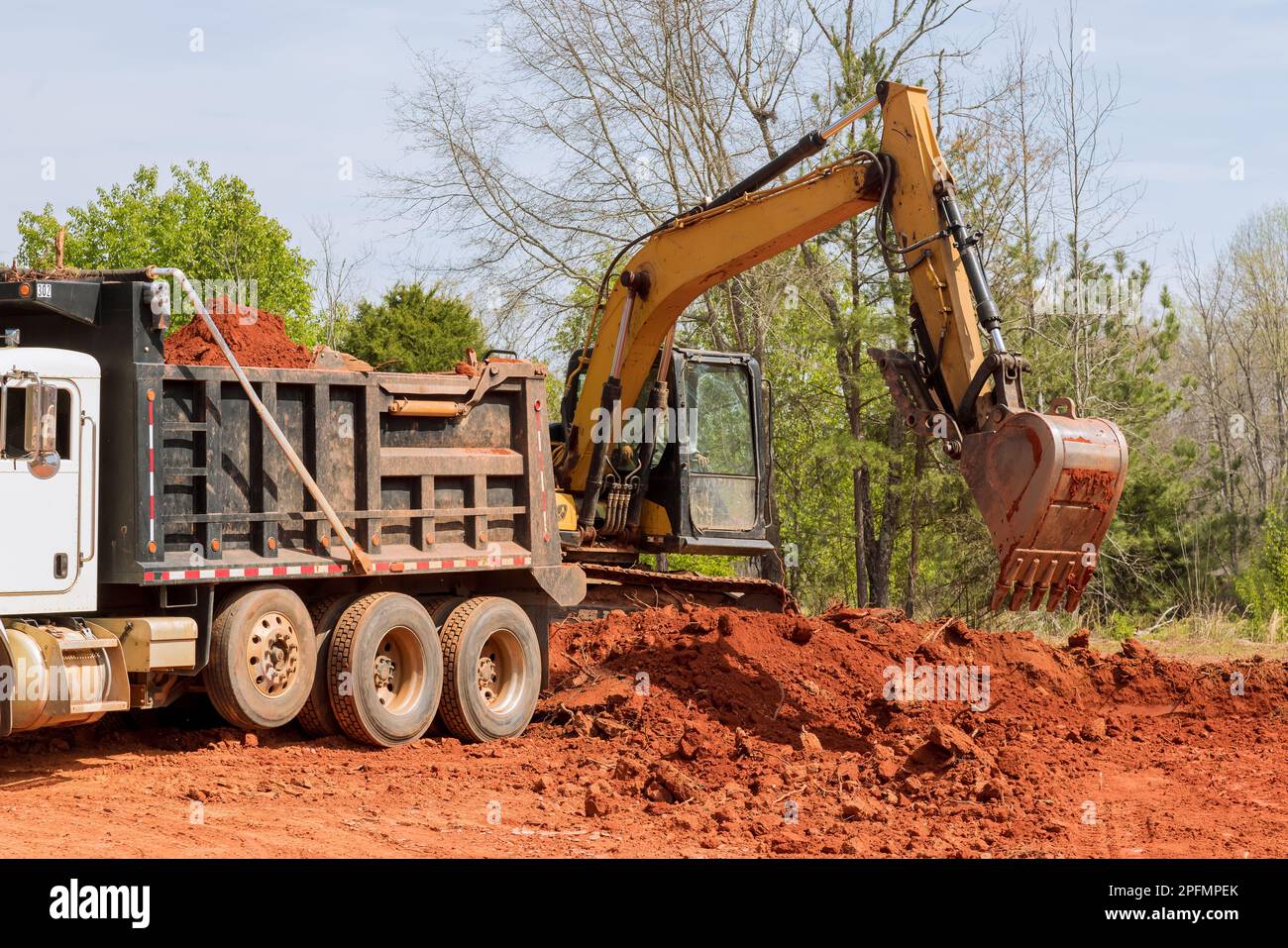 Loading earth into dump truck on construction site with an excavator ...