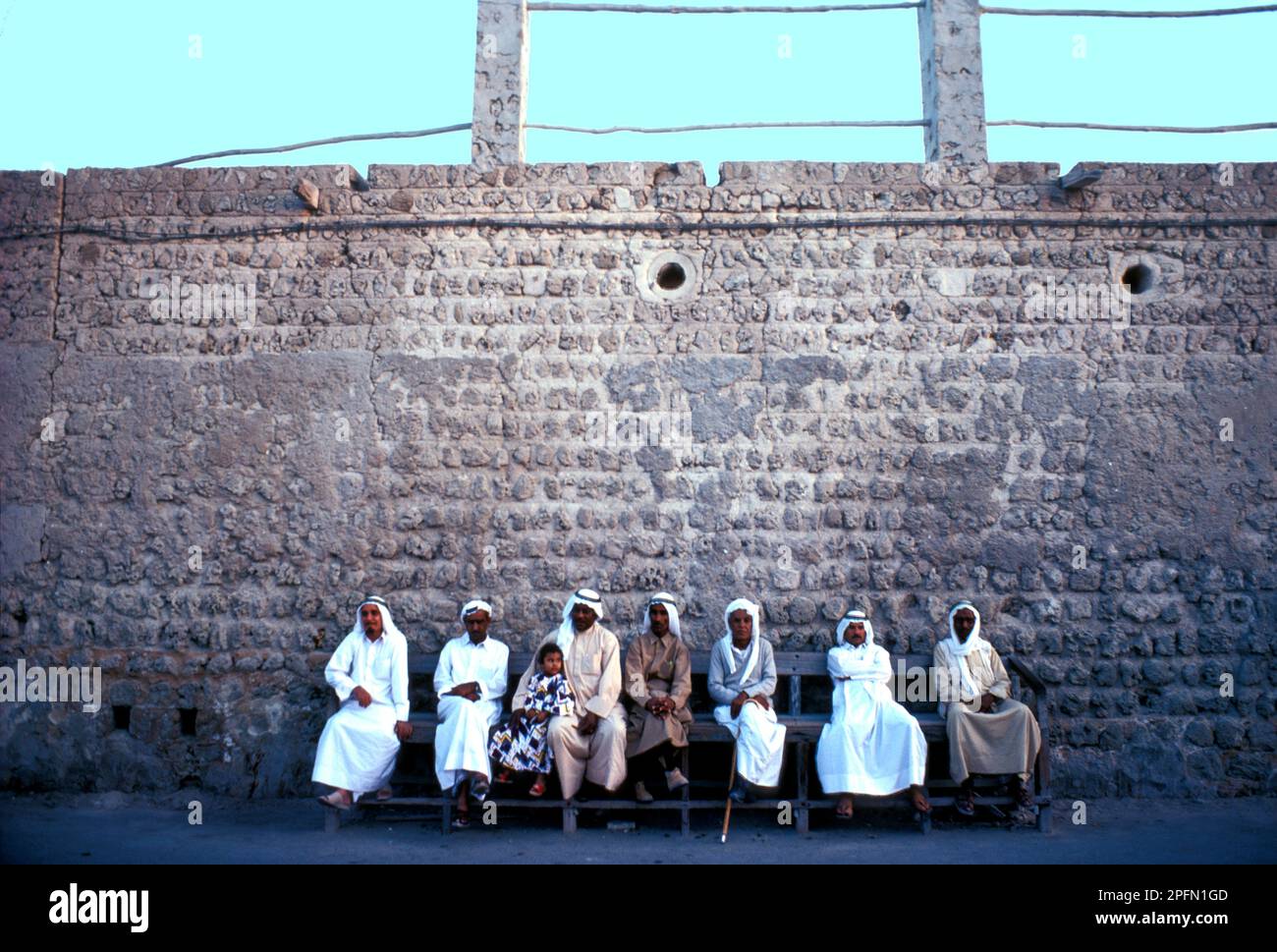 Arab men and a girl sitting on a street bench in Ajman during the fast ...