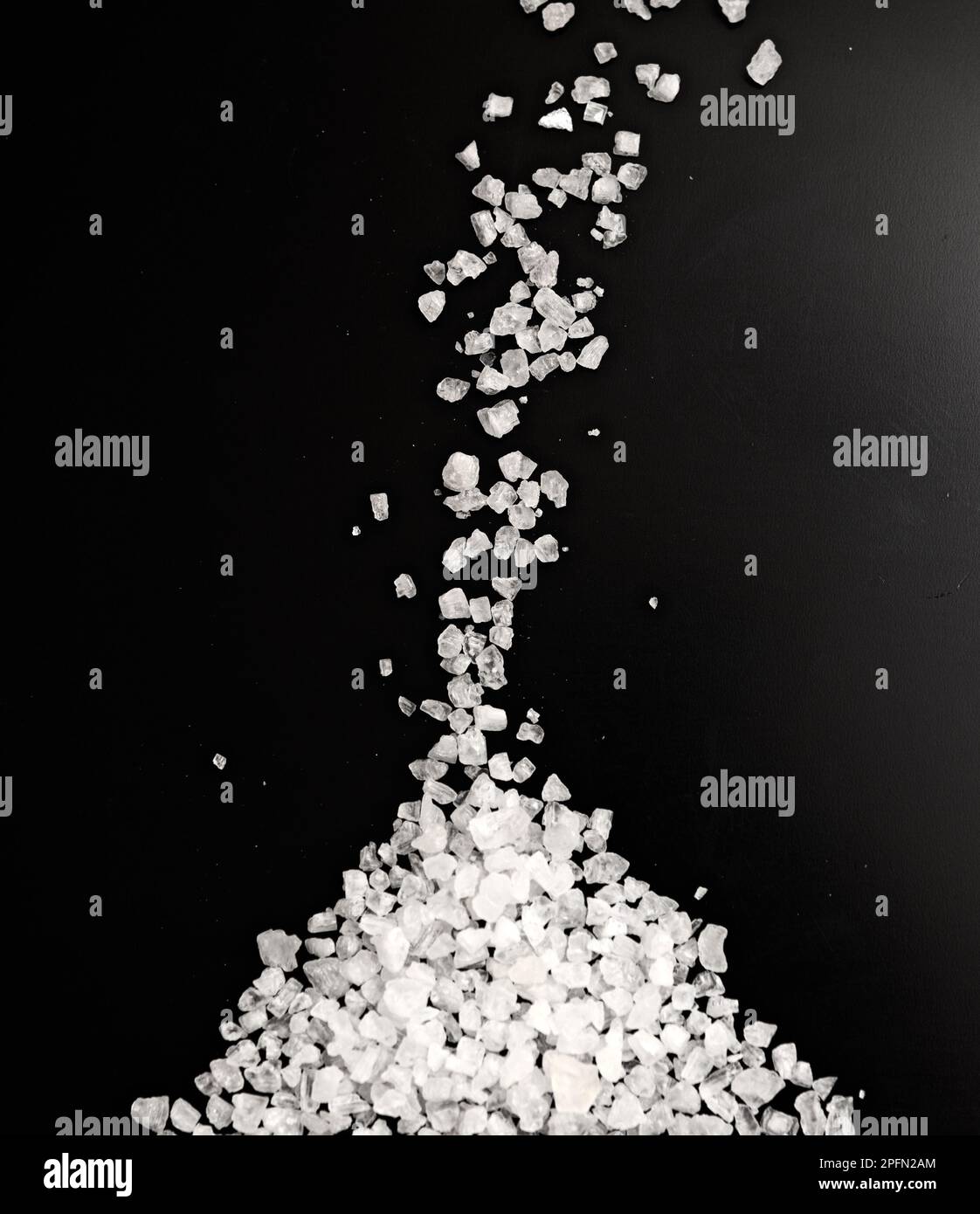 Sea salt falling on black background Stock Photo - Alamy