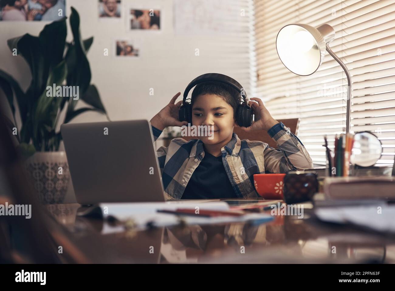 The classroom is closer than you think. an adorable little boy using a laptop and headphones ...