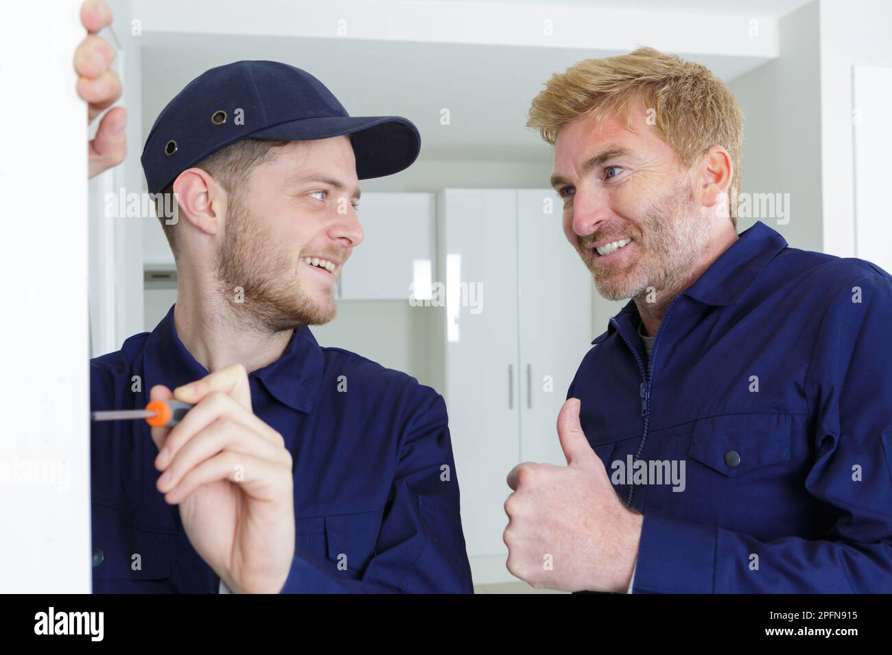 happy boss and smiling young carpenter install door lock Stock Photo ...