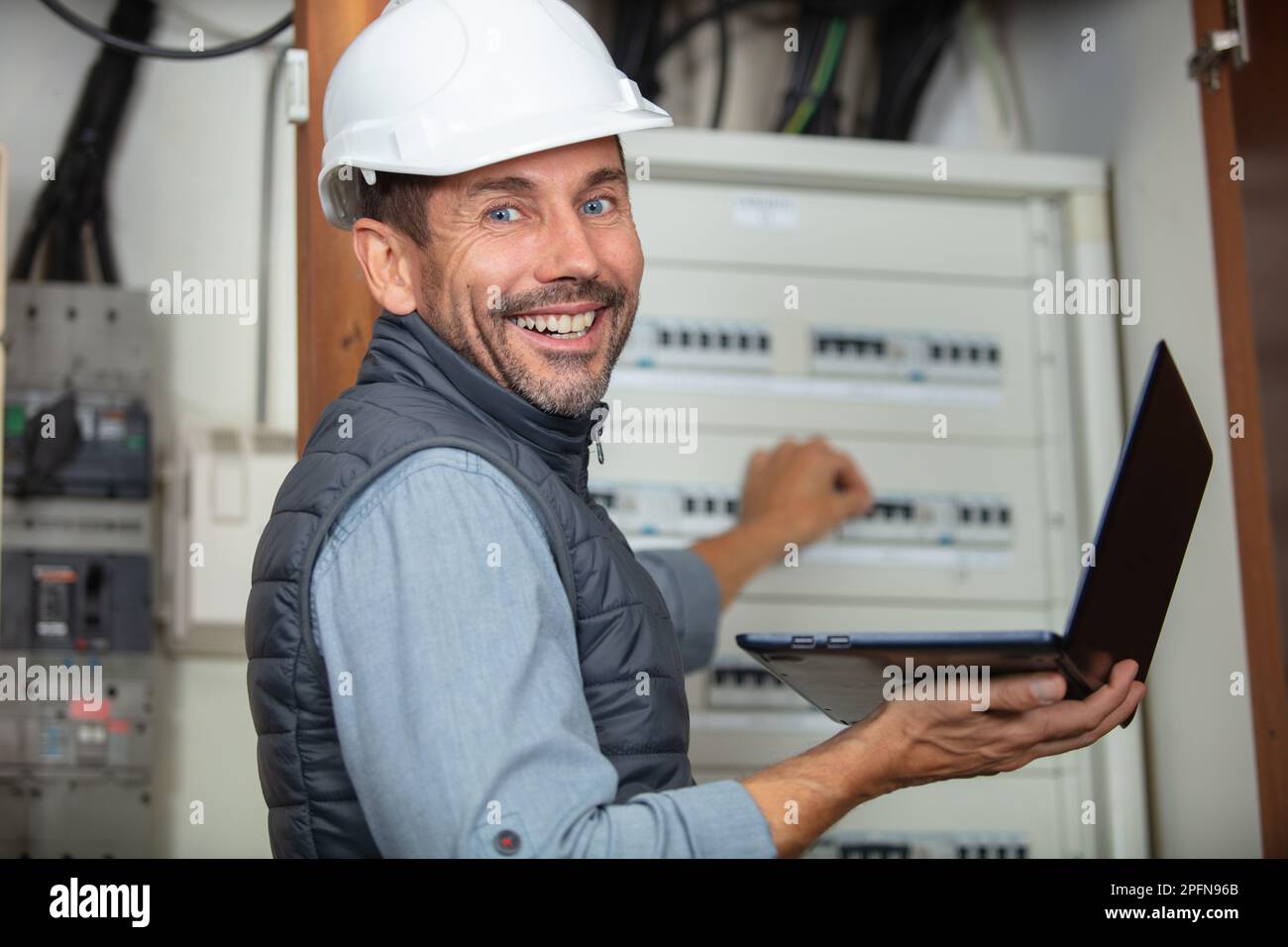 electrician with computer checking fuse box Stock Photo - Alamy