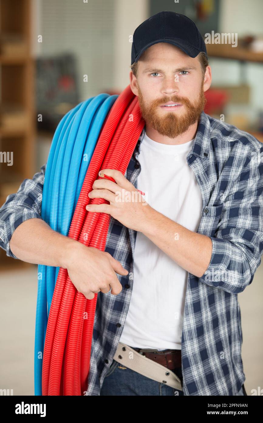 tradesman with rolls of blue and red corrugated plastic tubing Stock ...