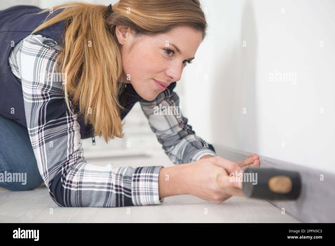 woman tapping mallet against skirting board Stock Photo - Alamy
