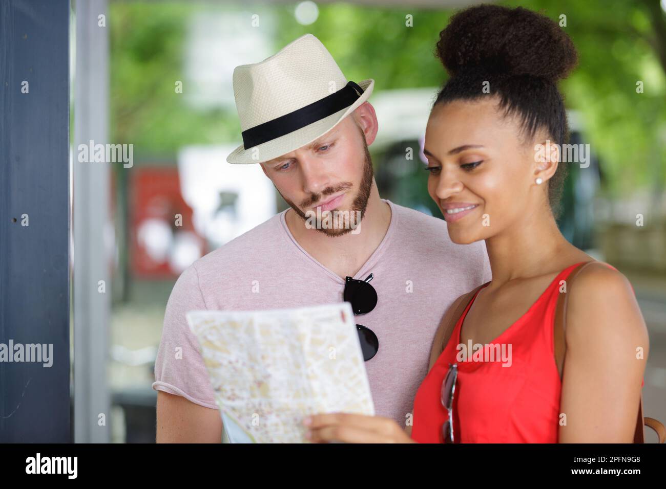 tourist couple in city looking up directions on map Stock Photo - Alamy
