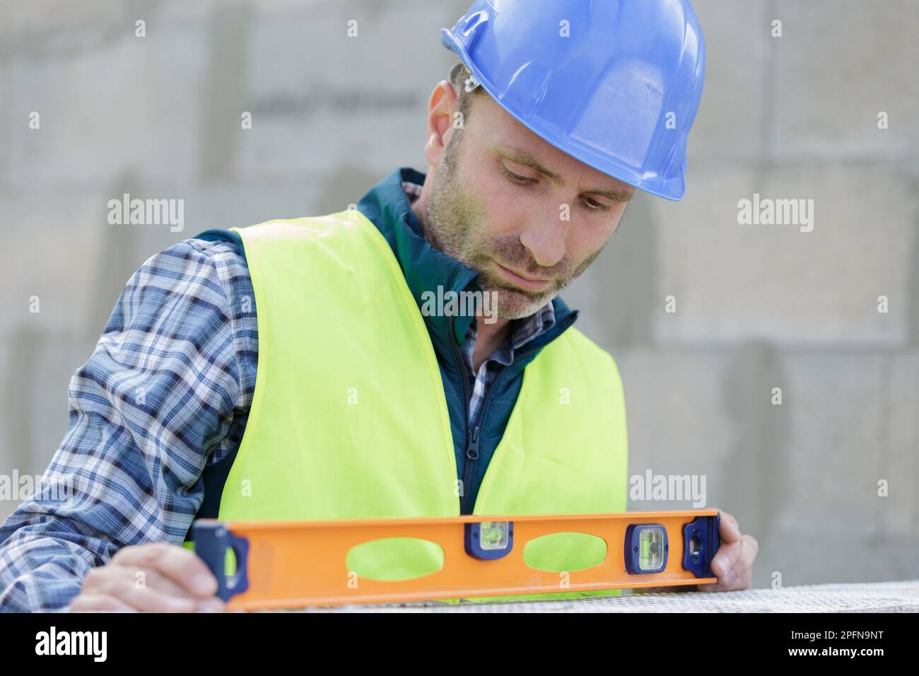 builder with spirit level on construction site Stock Photo - Alamy