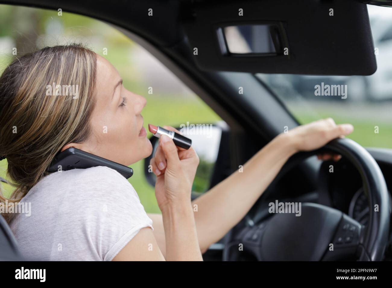 woman looking in rear view mirror applying lipstick Stock Photo - Alamy