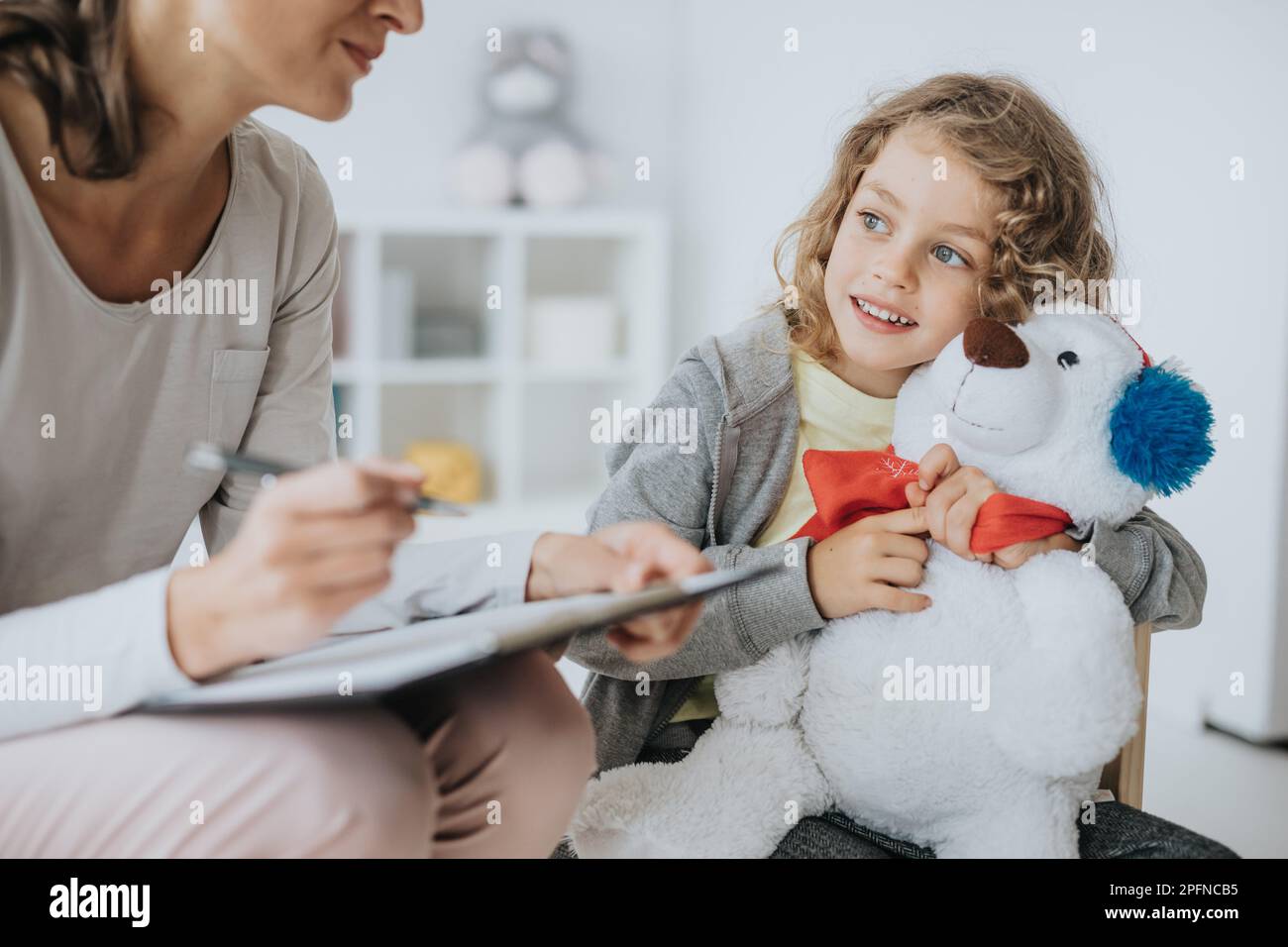 Little boy hugging a teddy bear during therapy with a psychologist ...