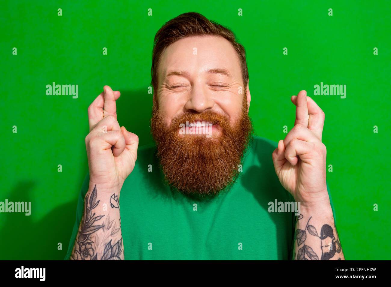 Photo of funky excited guy dressed t-shirt smiling fingers crossed ...