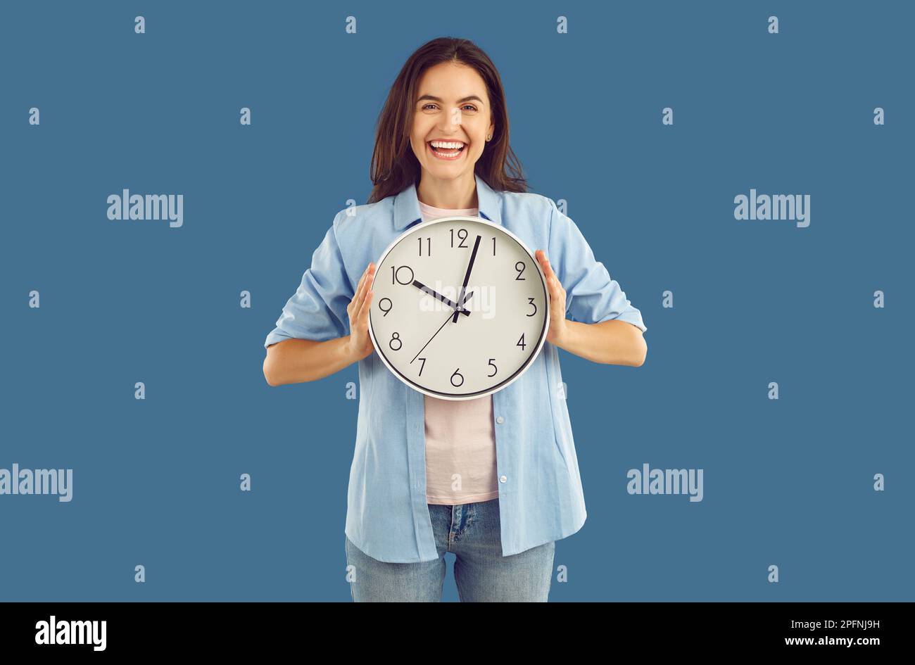 Happy excited young woman holding big wall clock Stock Photo - Alamy