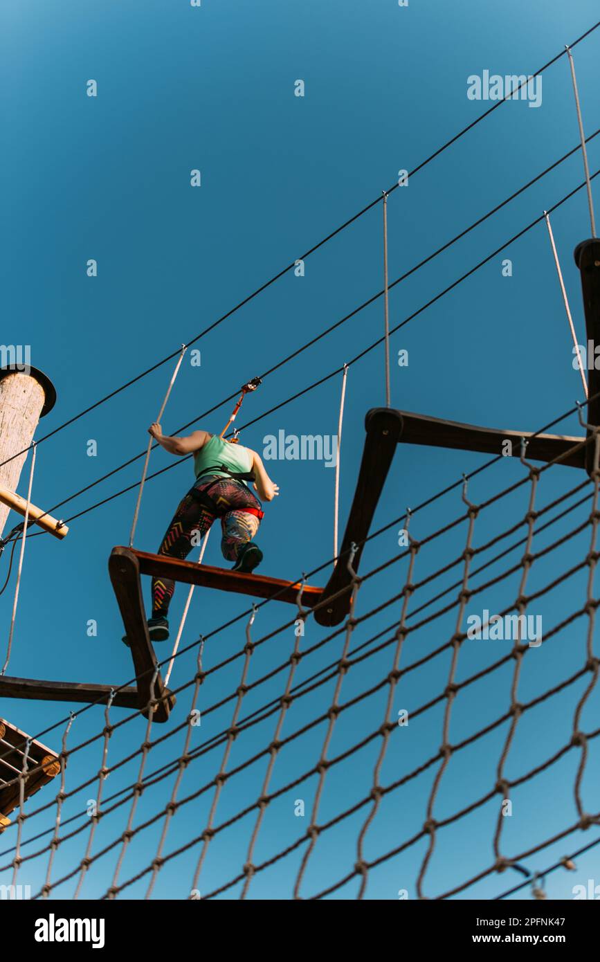 Woman running through the zig-zag pattern planks i the adventure park ...