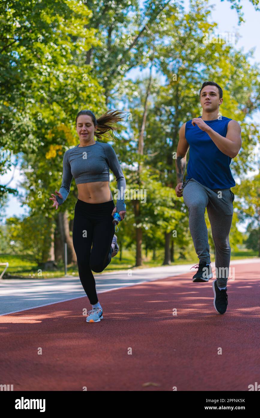 Two adult fitness models running in the park Stock Photo - Alamy