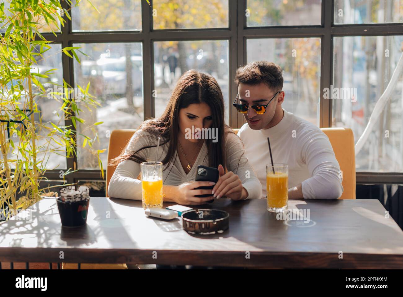 Friends socializing, having fun, and laughing drinking coffee in coffeehouse while fooling ...