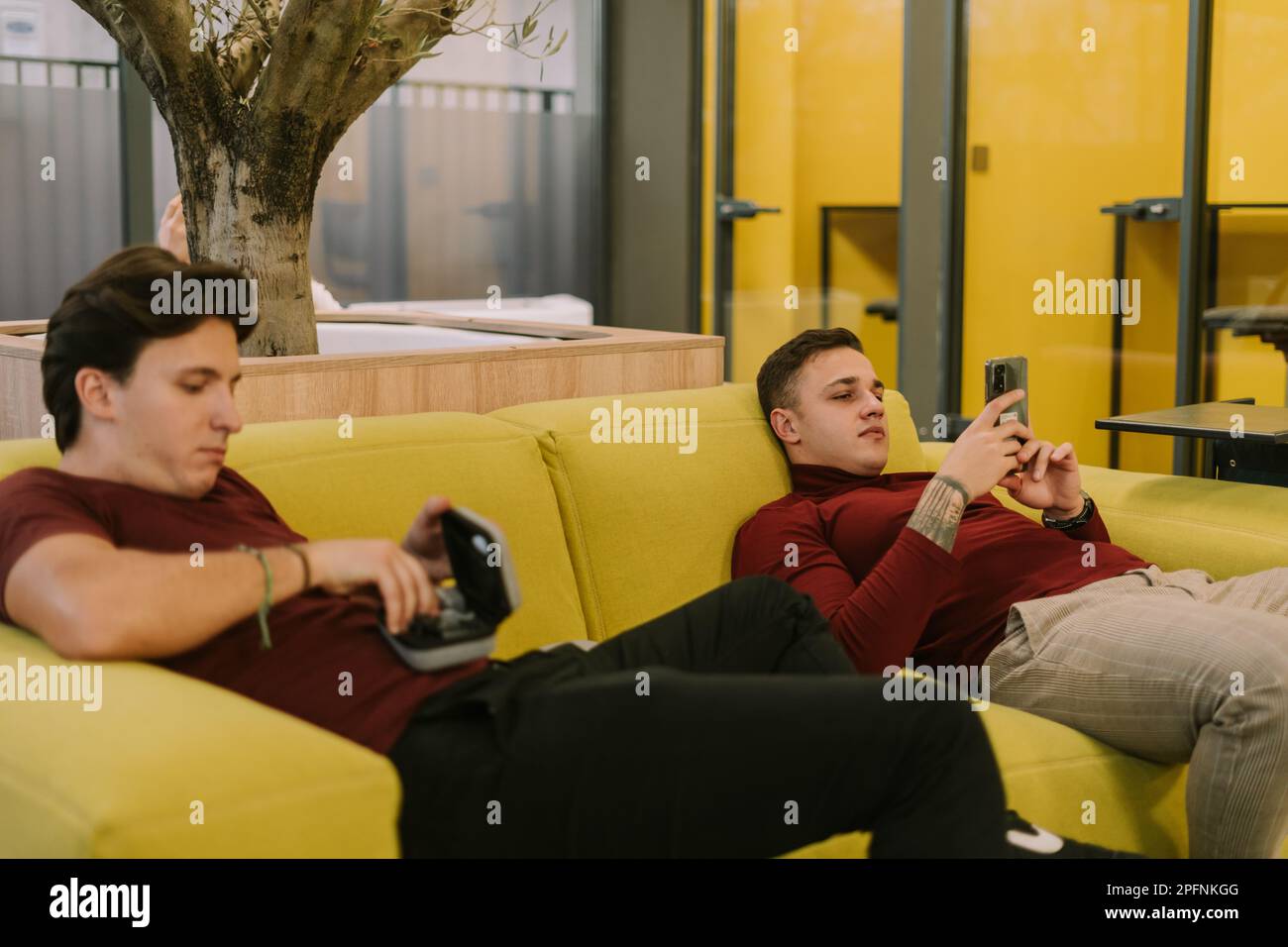 Good looking male colleagues lying on a yellow sofa at modern co ...