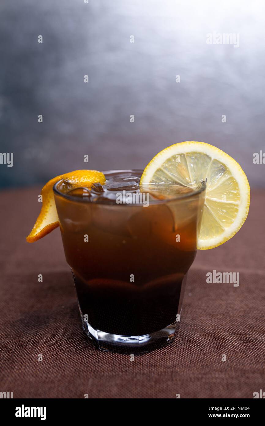 alcoholic drink with Cola and a slice of lemon in a glass Stock Photo - Alamy