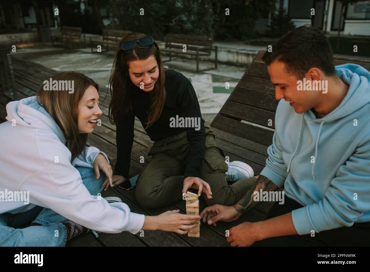 Three happy friends having fun while playing jenga and sitting on the ...