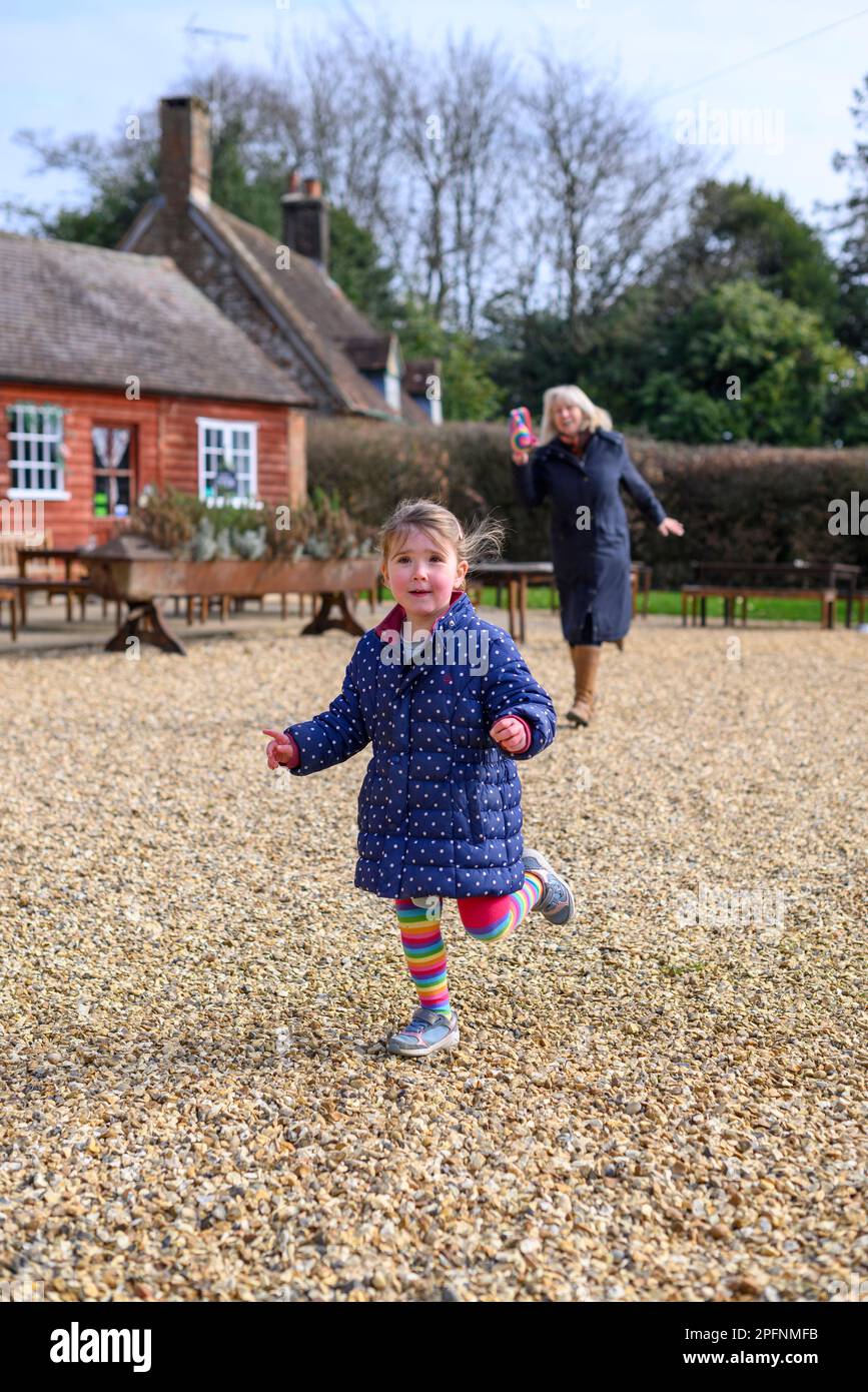 Child running with senior woman following behind, chasing Stock Photo ...
