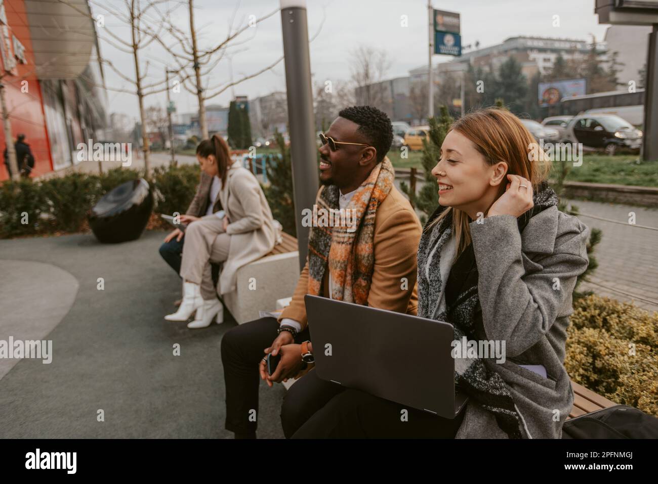 Business colleagues smiling and working while sitting at the park near ...