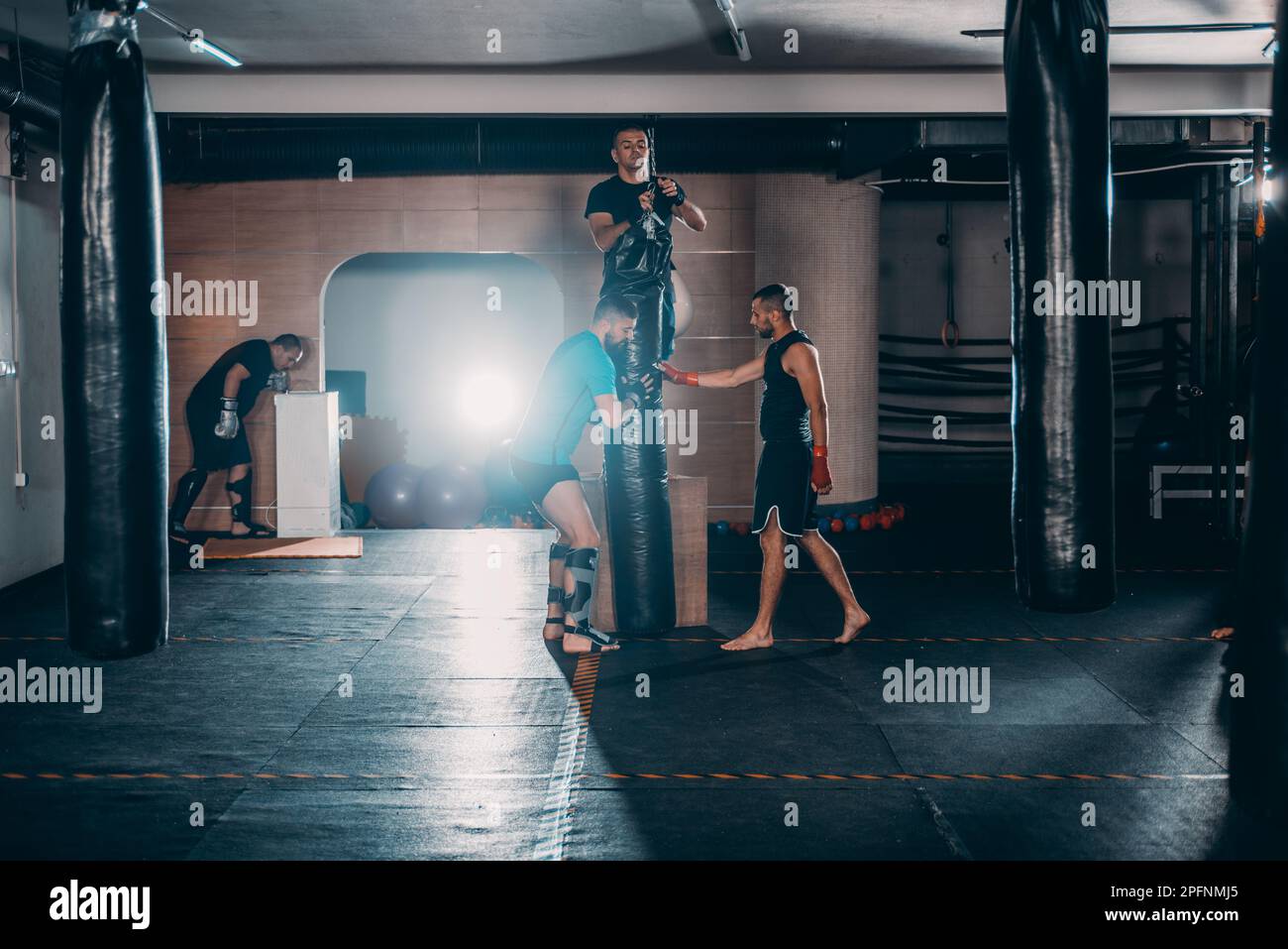 Sporty man set up boxing bag on the wall in underground garage Stock ...