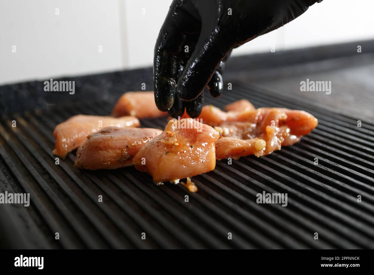 Cook preparing chicken meat on hot grill pan. White poultry fillet ...