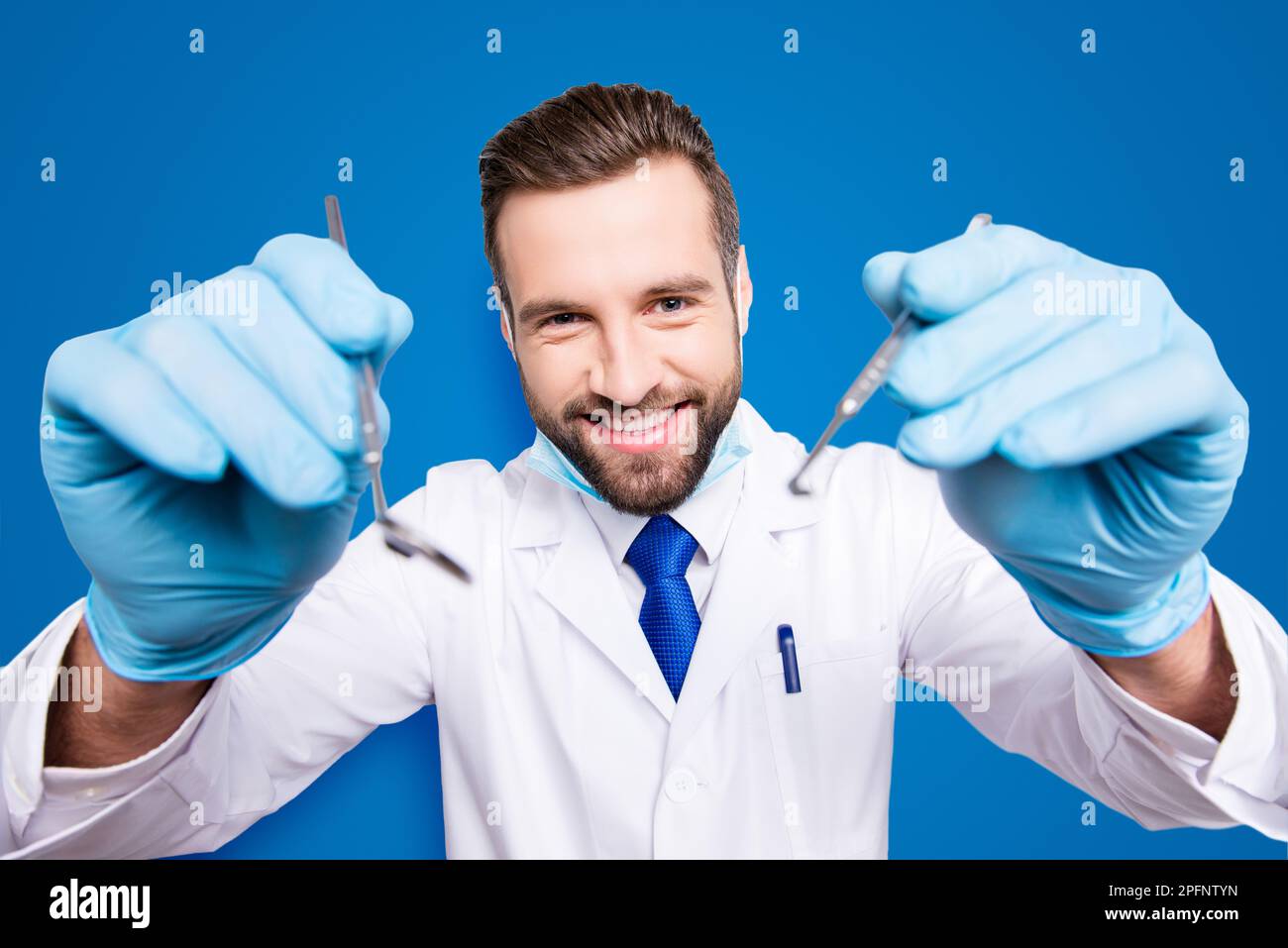 Portrait of positive comic dentist with stubble in white lab coat, blue ...