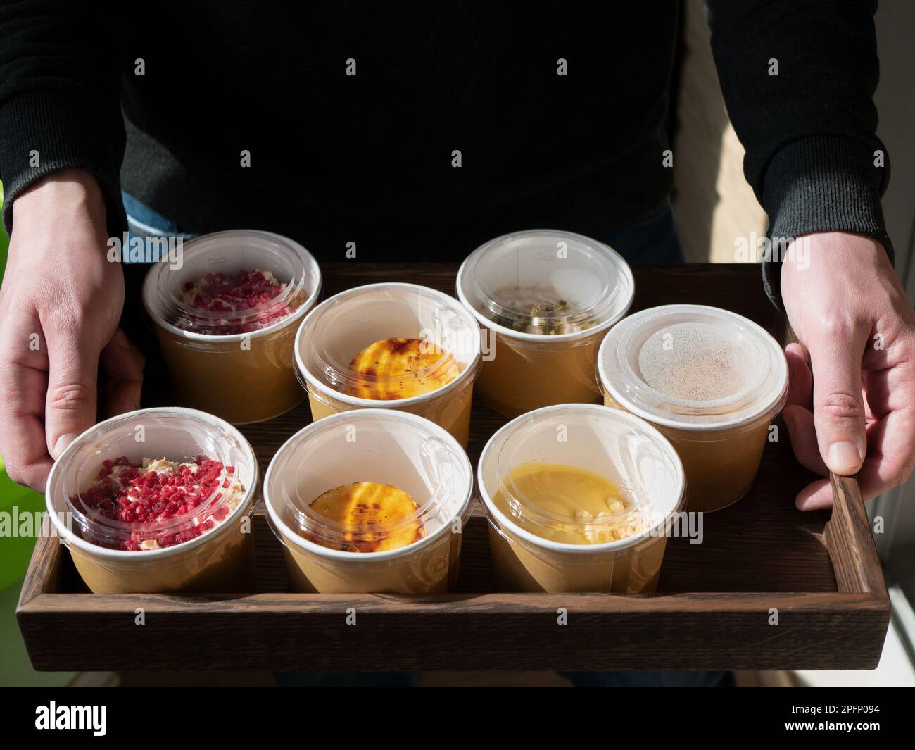 Person holds a tray with different food in disposable containers ...