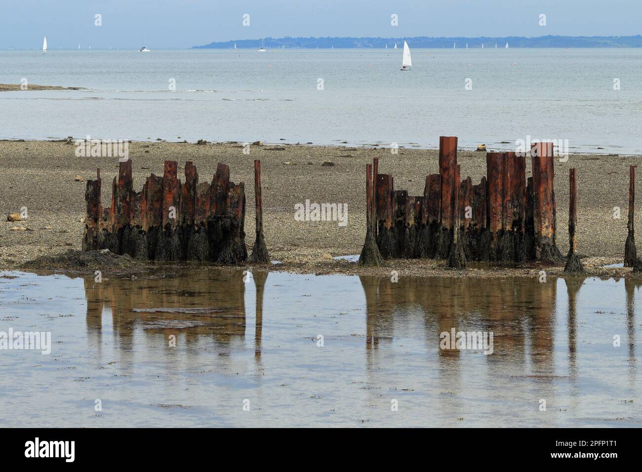 Corroding sheet piles on the beach near Lymington with reflections in ...
