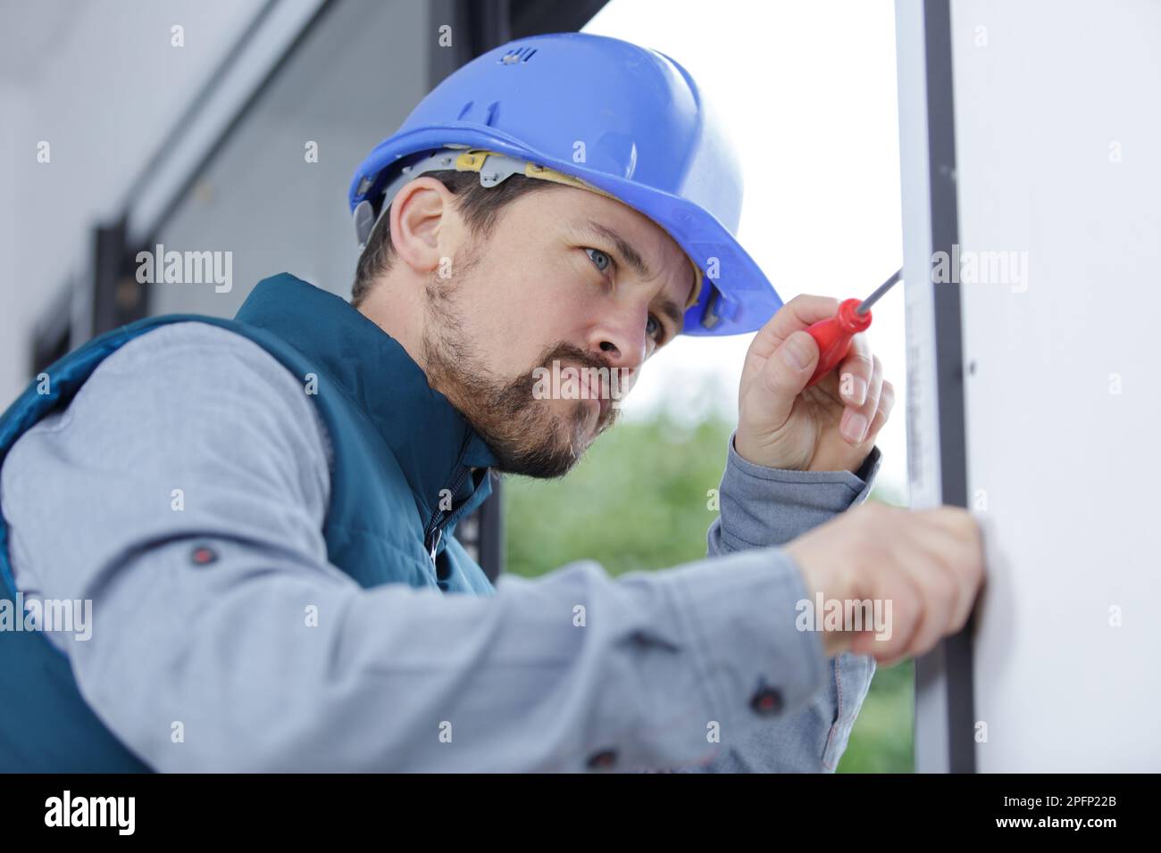 handyman in uniform fixing glass window with screwdriver Stock Photo ...