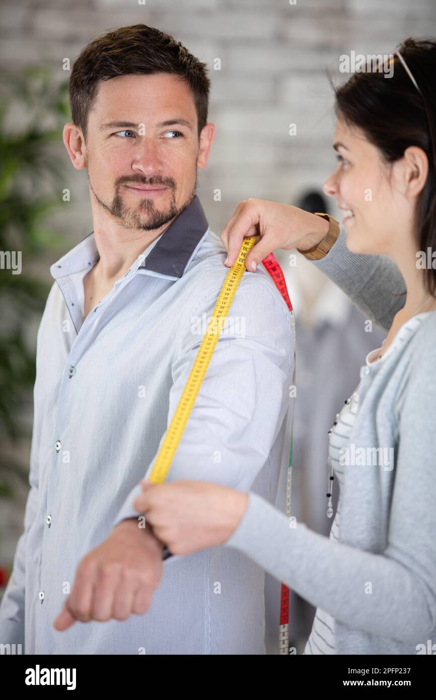 female tailor taking measurement of coat Stock Photo - Alamy