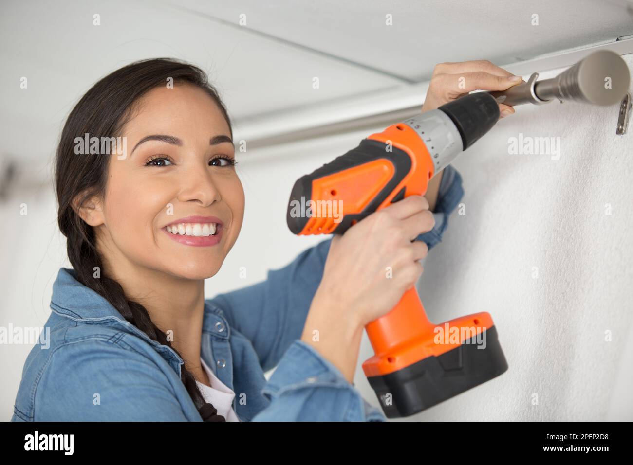 woman securing curtain rail support witha cordless drill Stock Photo ...