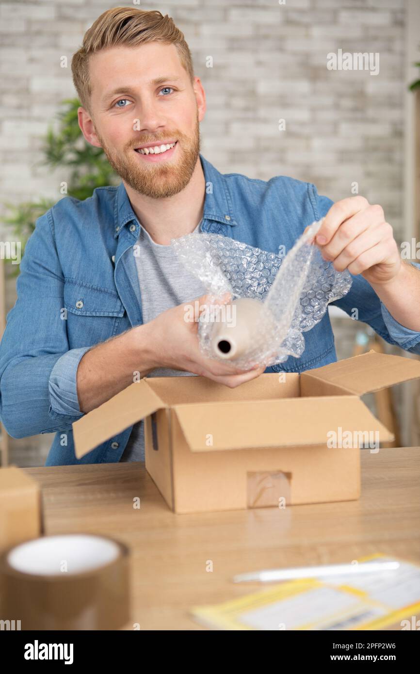 happy man unpacking moving box at new home Stock Photo - Alamy