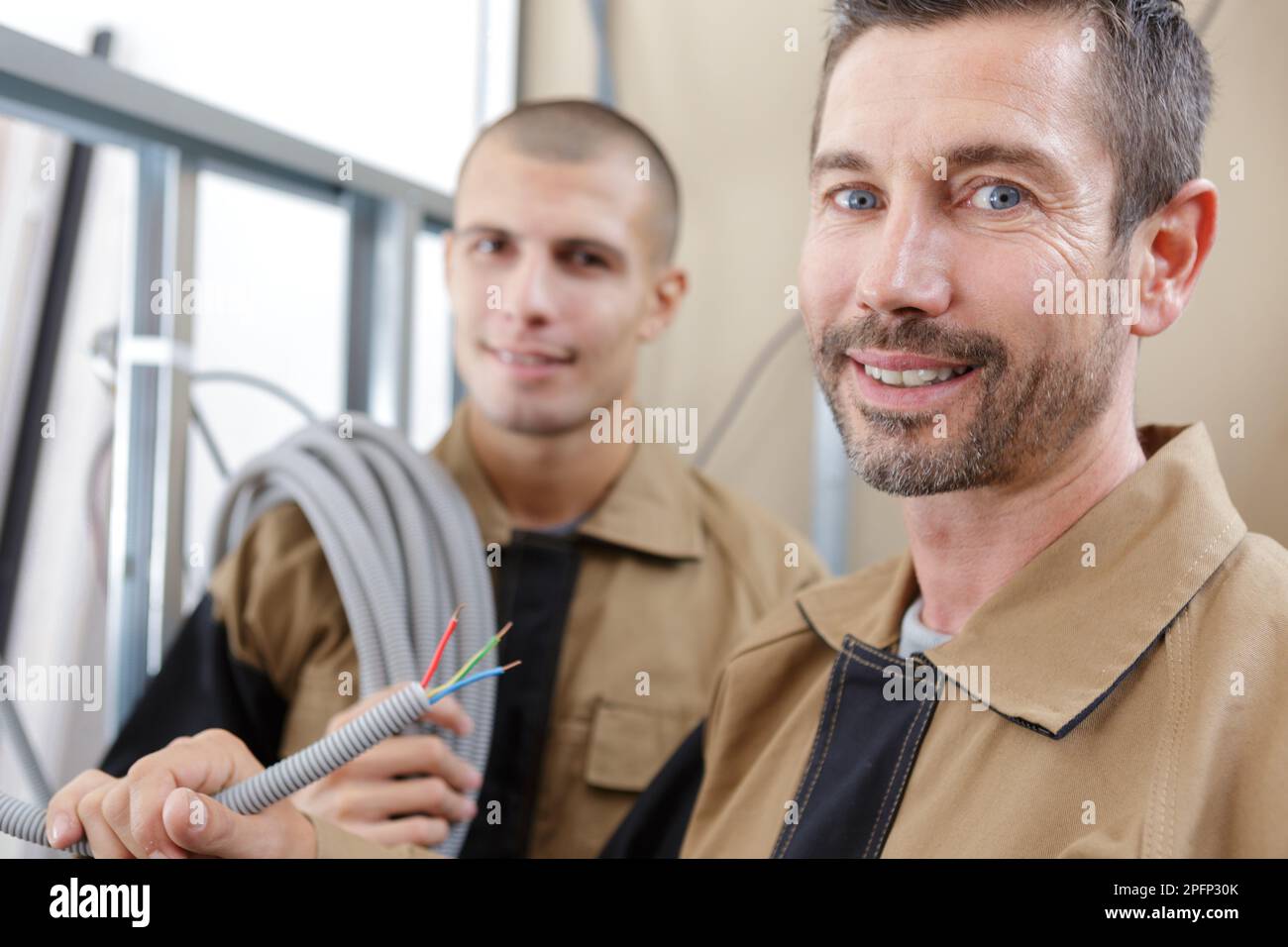 a happy electrician holding corrugated wire Stock Photo - Alamy