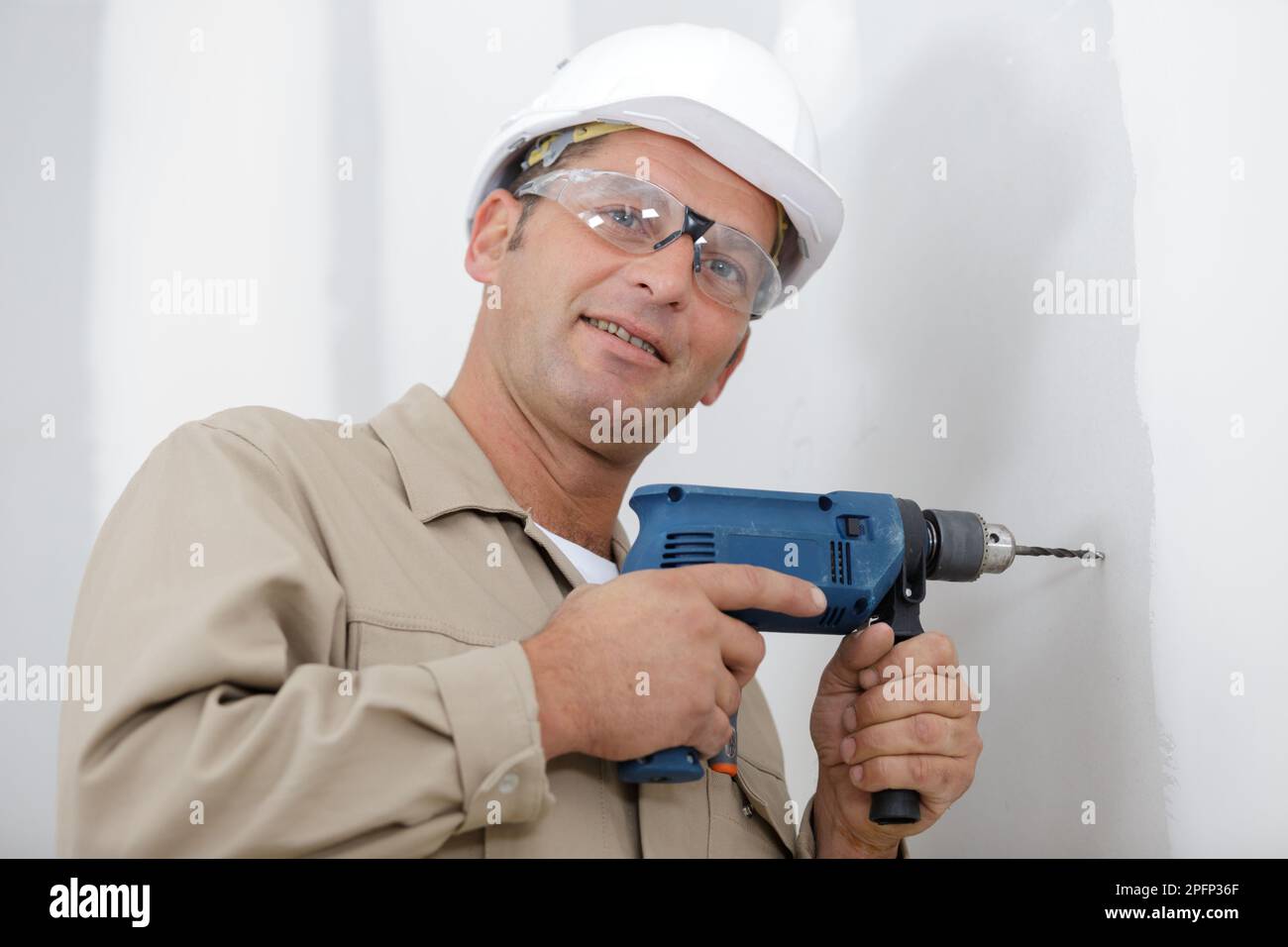 man drilling the wall with drill perforator Stock Photo - Alamy