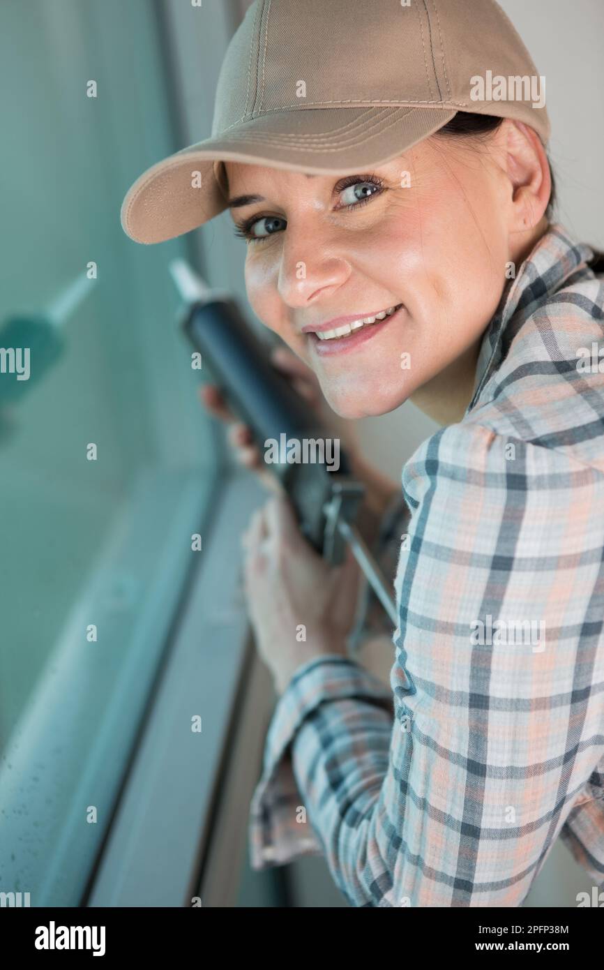 happy woman applying silicone to window Stock Photo - Alamy
