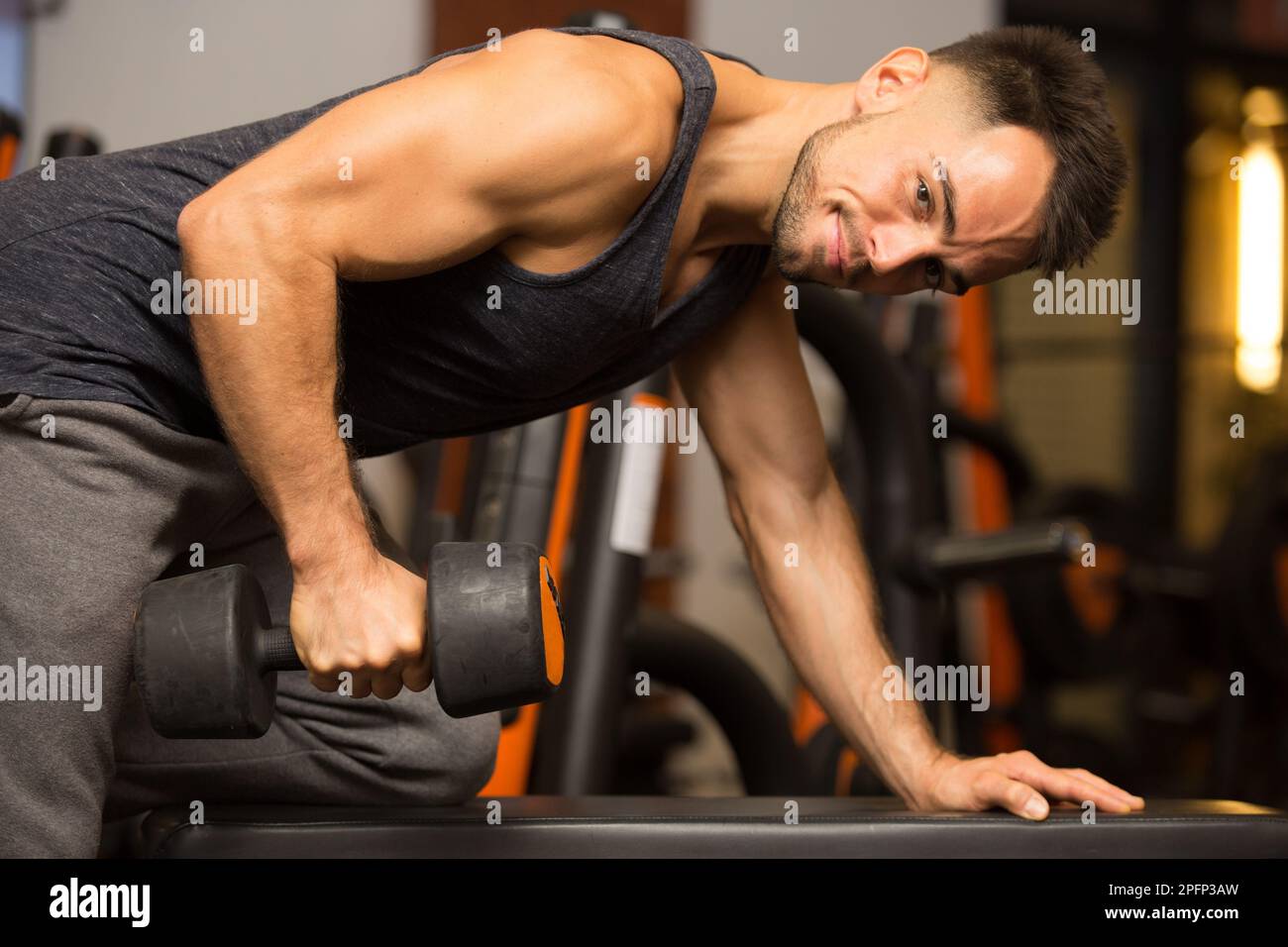 young man doing one-arm dumbbell rows on bench Stock Photo - Alamy