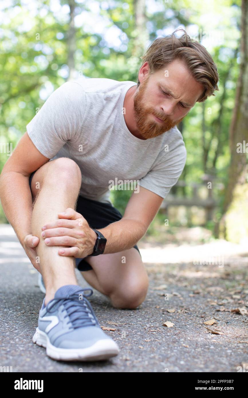 young man holding sore and painful muscle Stock Photo - Alamy