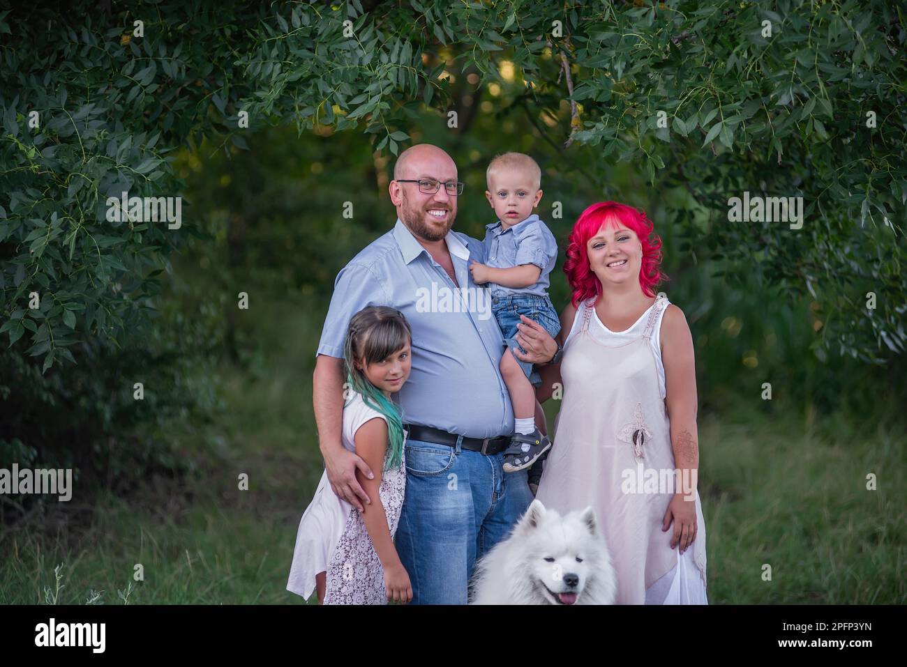 Portrait of bright, unusual, diversity family in nature with Samoyed ...