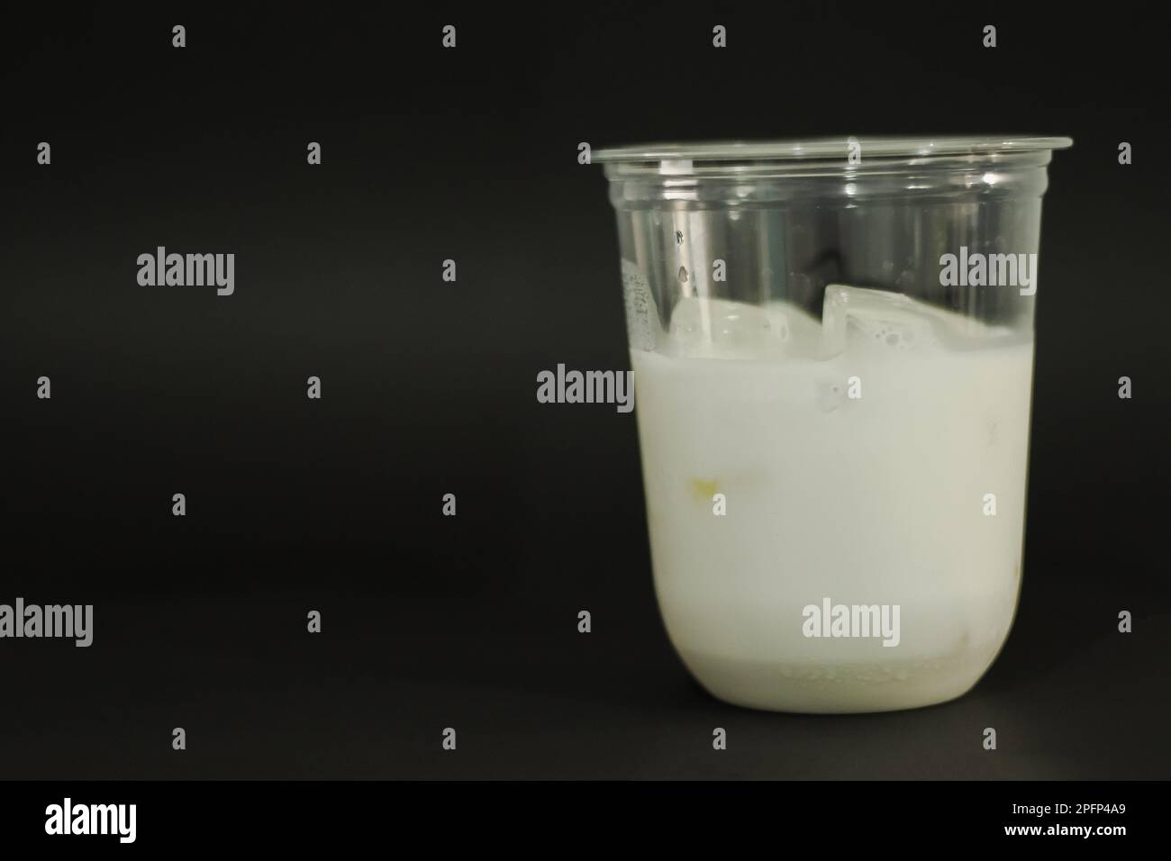 Milk and ice cubes in a plastic glass on a black background Stock Photo ...