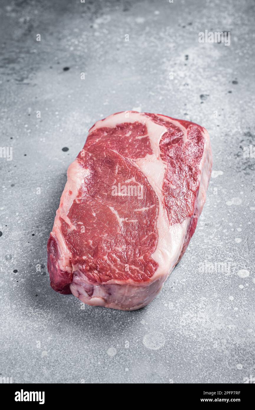 Raw Rib Eye Steak, beef marbled meat on butcher board. Gray background ...