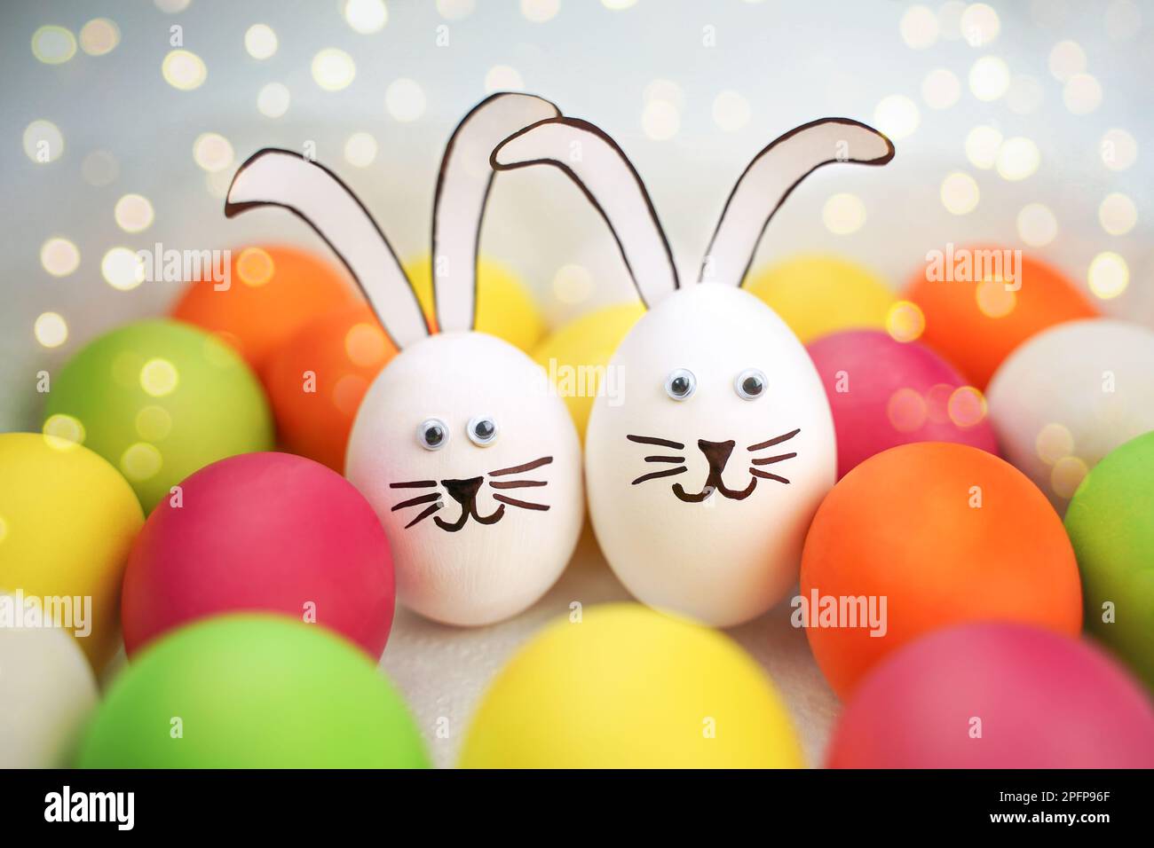 Funny bunnies couple on background of colorful eggs and bokeh. Cheerful ...