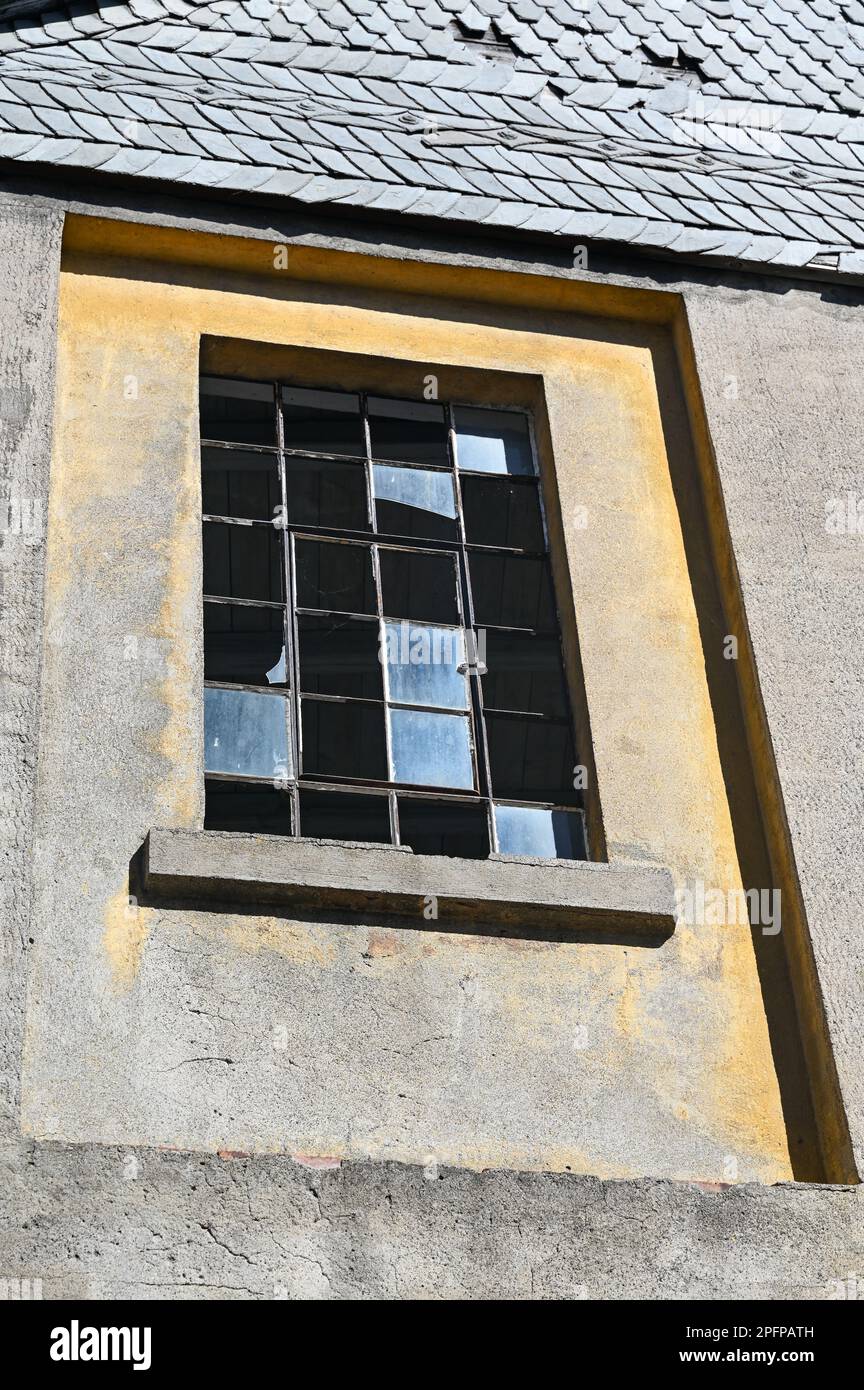 Facade of an old house with metal grille windows and broken glass panes ...